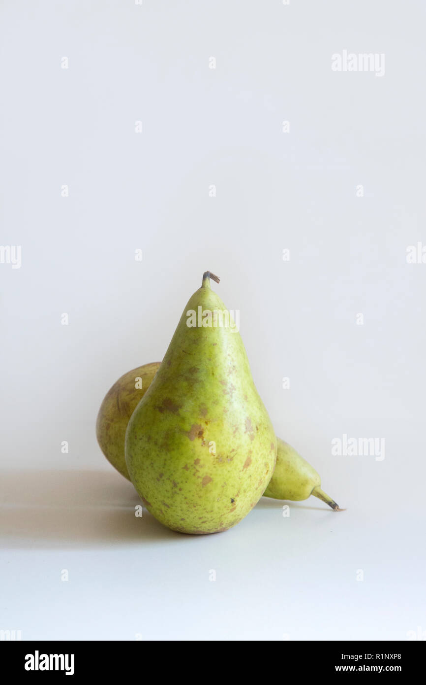 Two green pears sitting on a white background in soft lighting with ...