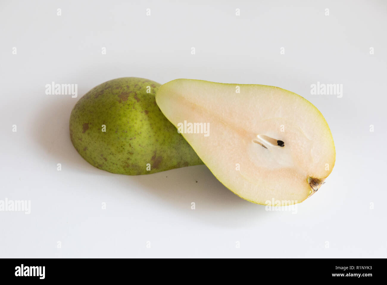 Pear cut in half length ways on a white background Stock Photo - Alamy
