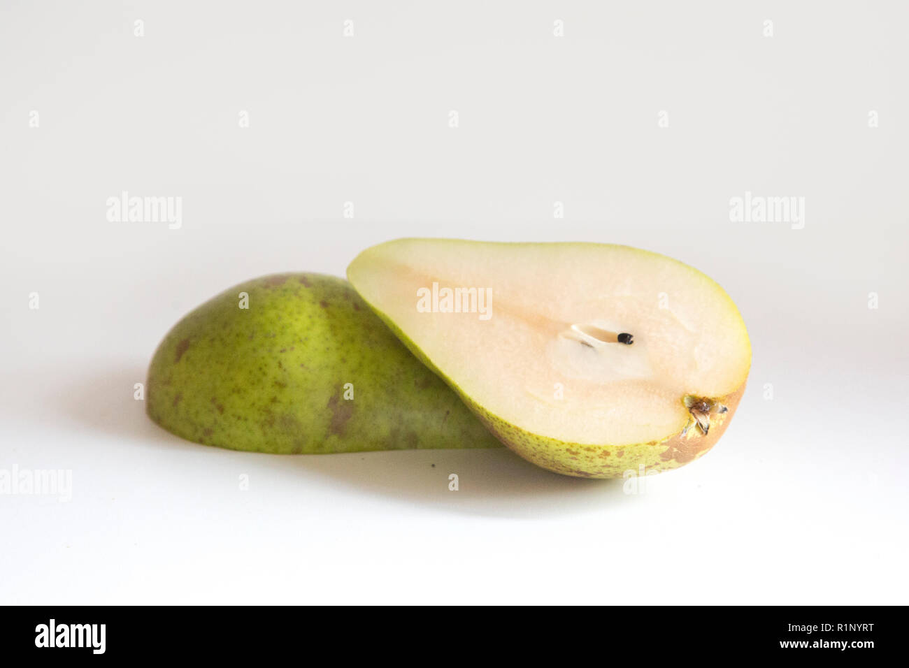 Pear cut in half length ways on a white background Stock Photo - Alamy