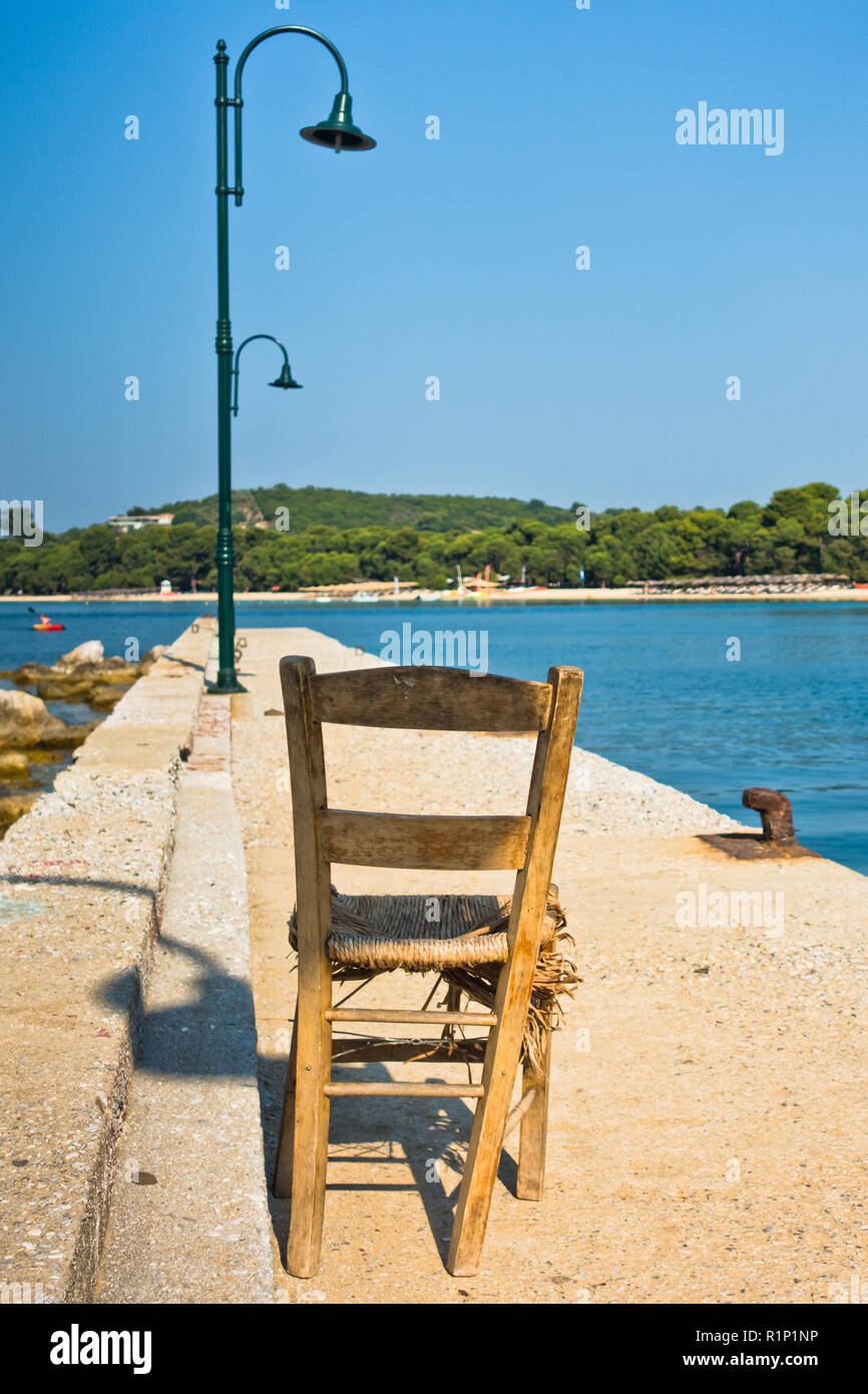 Old wooden chair on a pier in front of Koukounaries beach, morning at ...