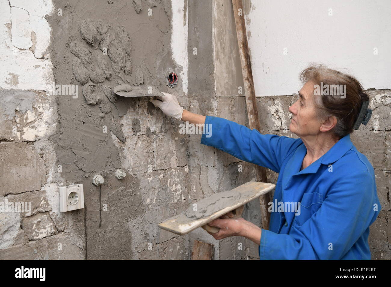 Woman worker plastering concrete at wall of house construction Stock ...