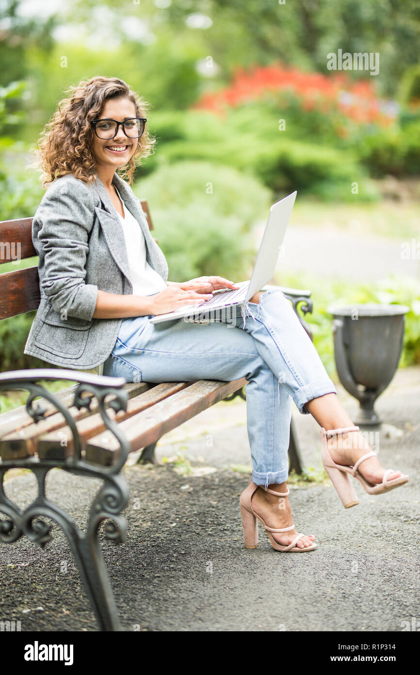 Business woman sitting on bench in park and working on laptop Stock ...