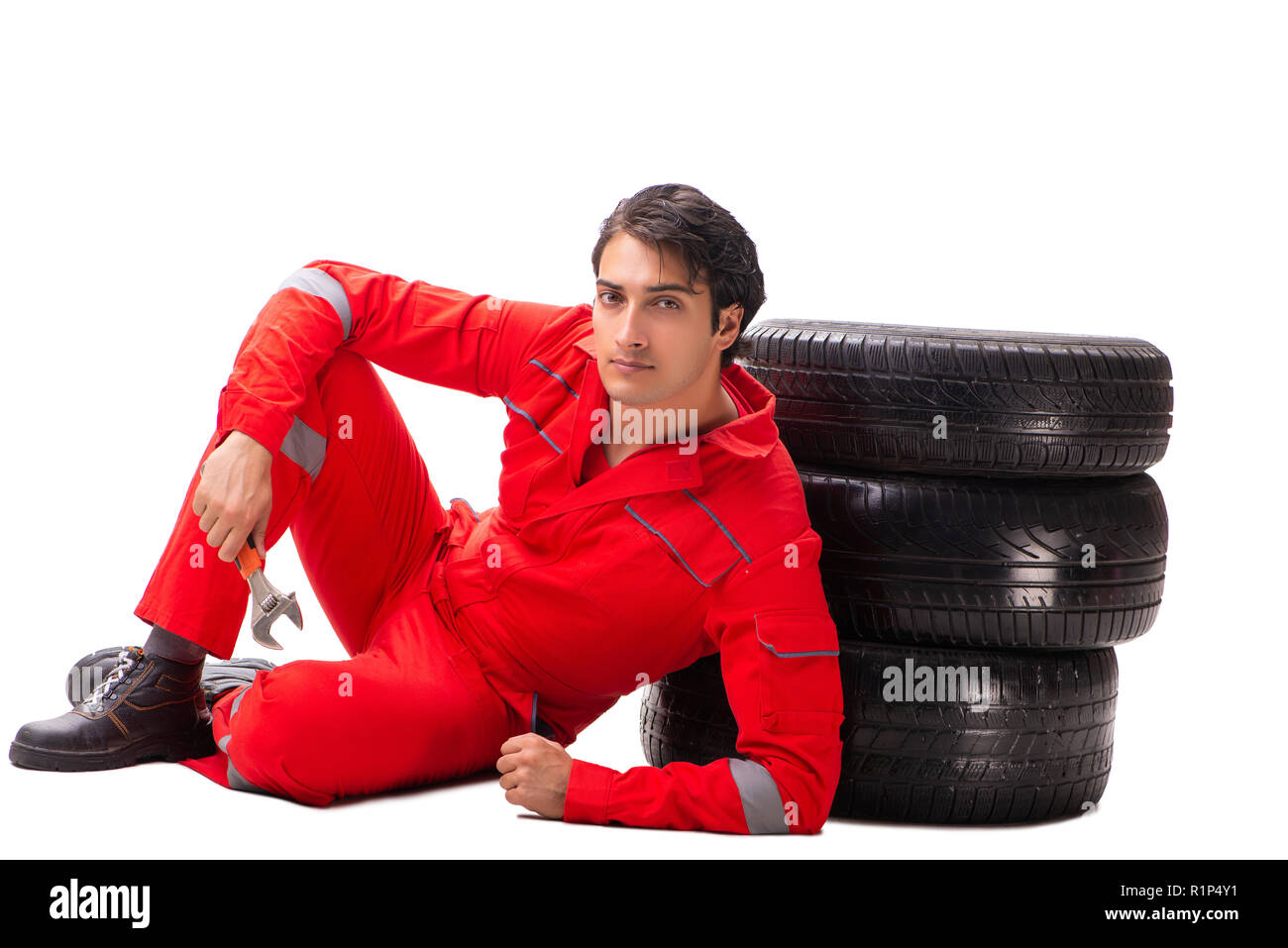 Young garage worker with tyre isolated on white Stock Photo - Alamy