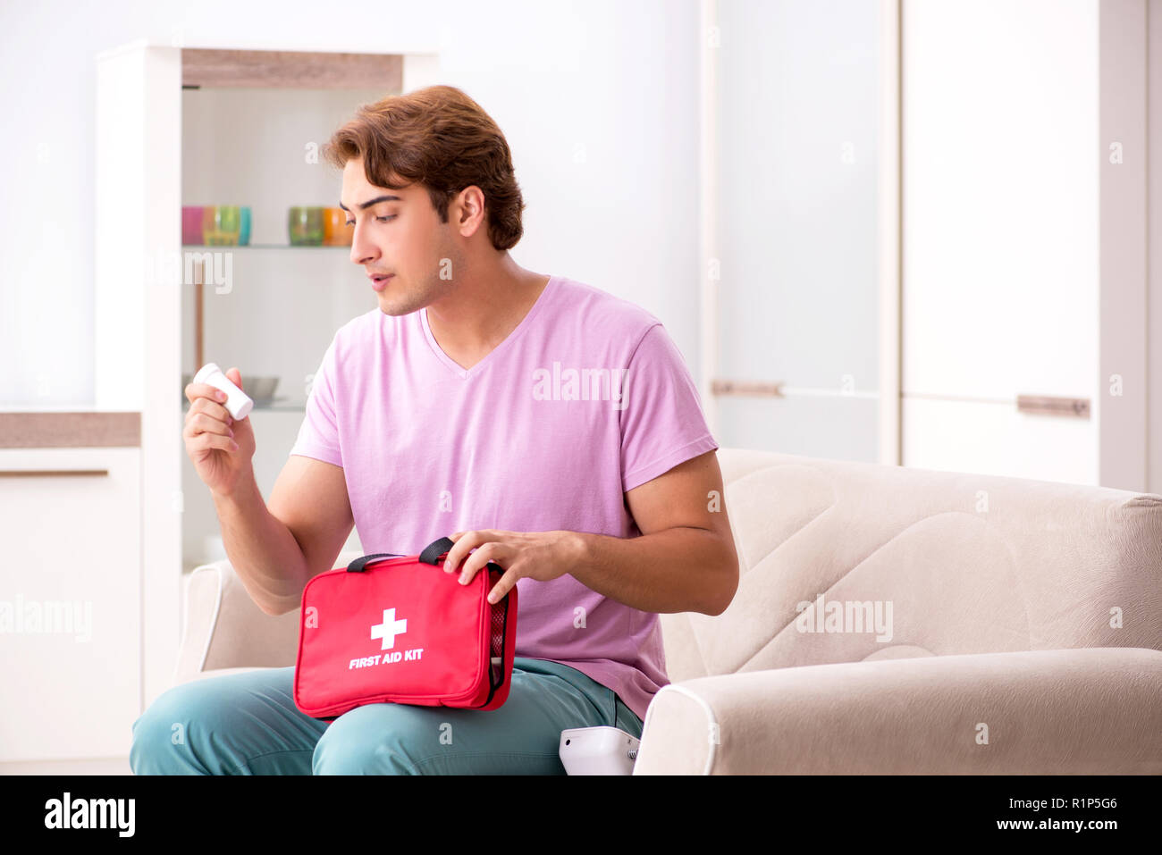 Sick man at home with first aid kit Stock Photo - Alamy