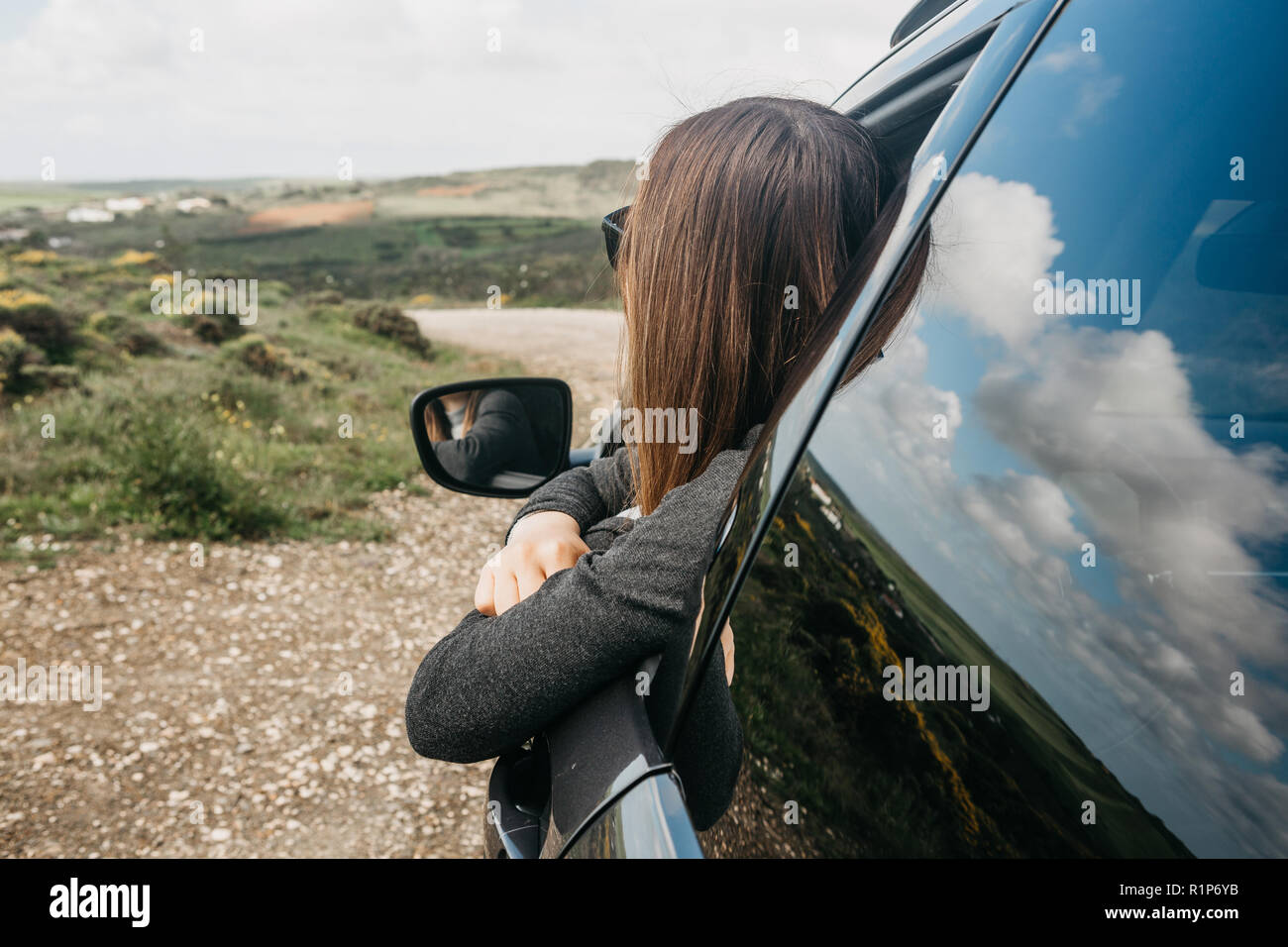 A girl driver or a female traveler inside the car looks out the window ...