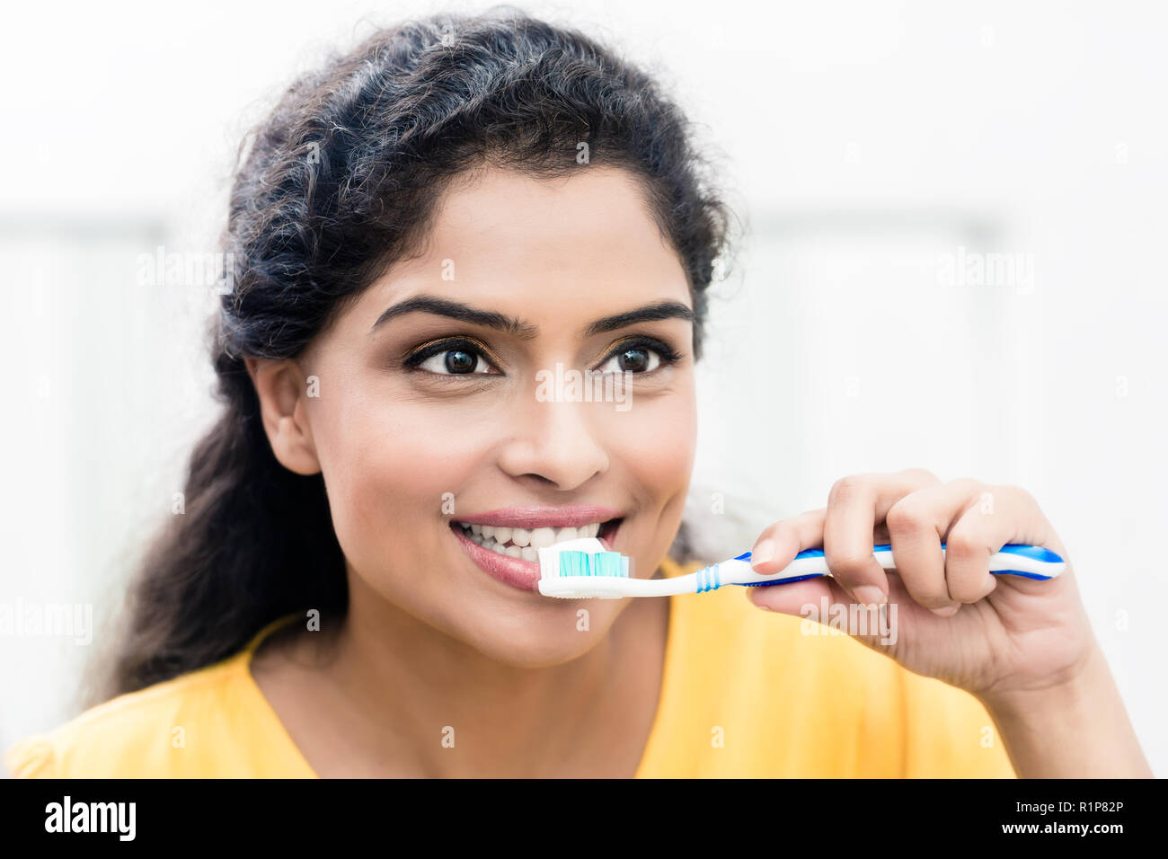 Close up portrait of a beautiful young woman brushing teeth in the ...