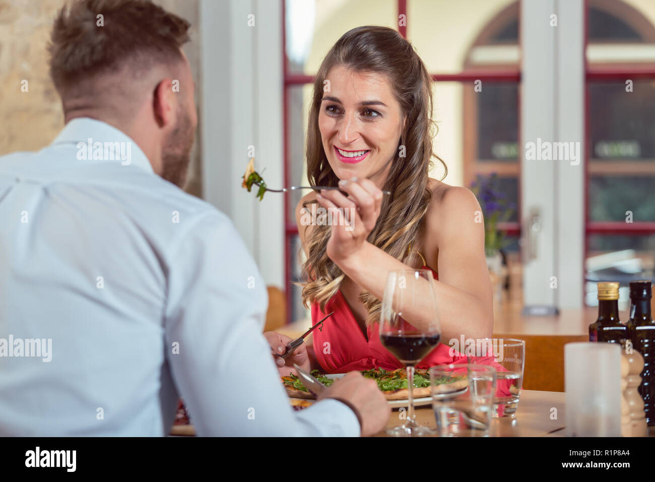 Young woman on date feeding her boyfriend at restaurant Stock Photo - Alamy