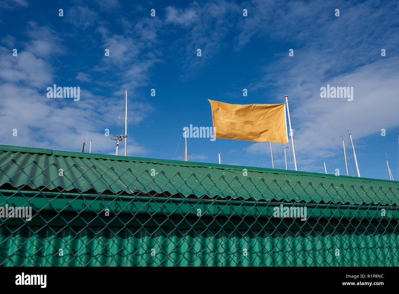 An orange flag waving in the wind with room for copy with green shed in ...