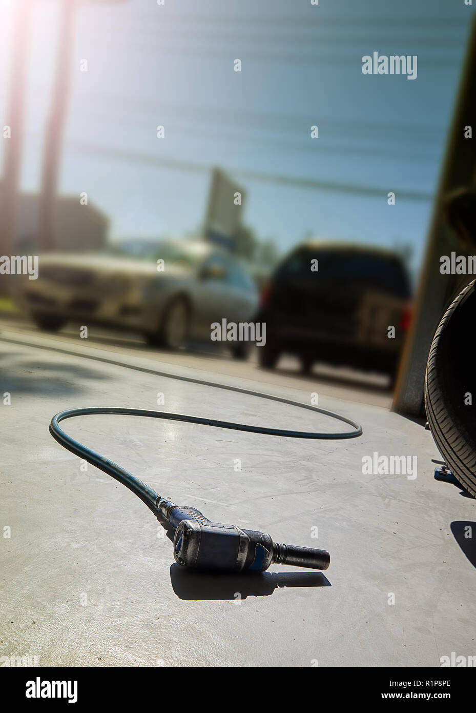 Blue impact wrench rattle gun with air hose on a workshop floor with ...