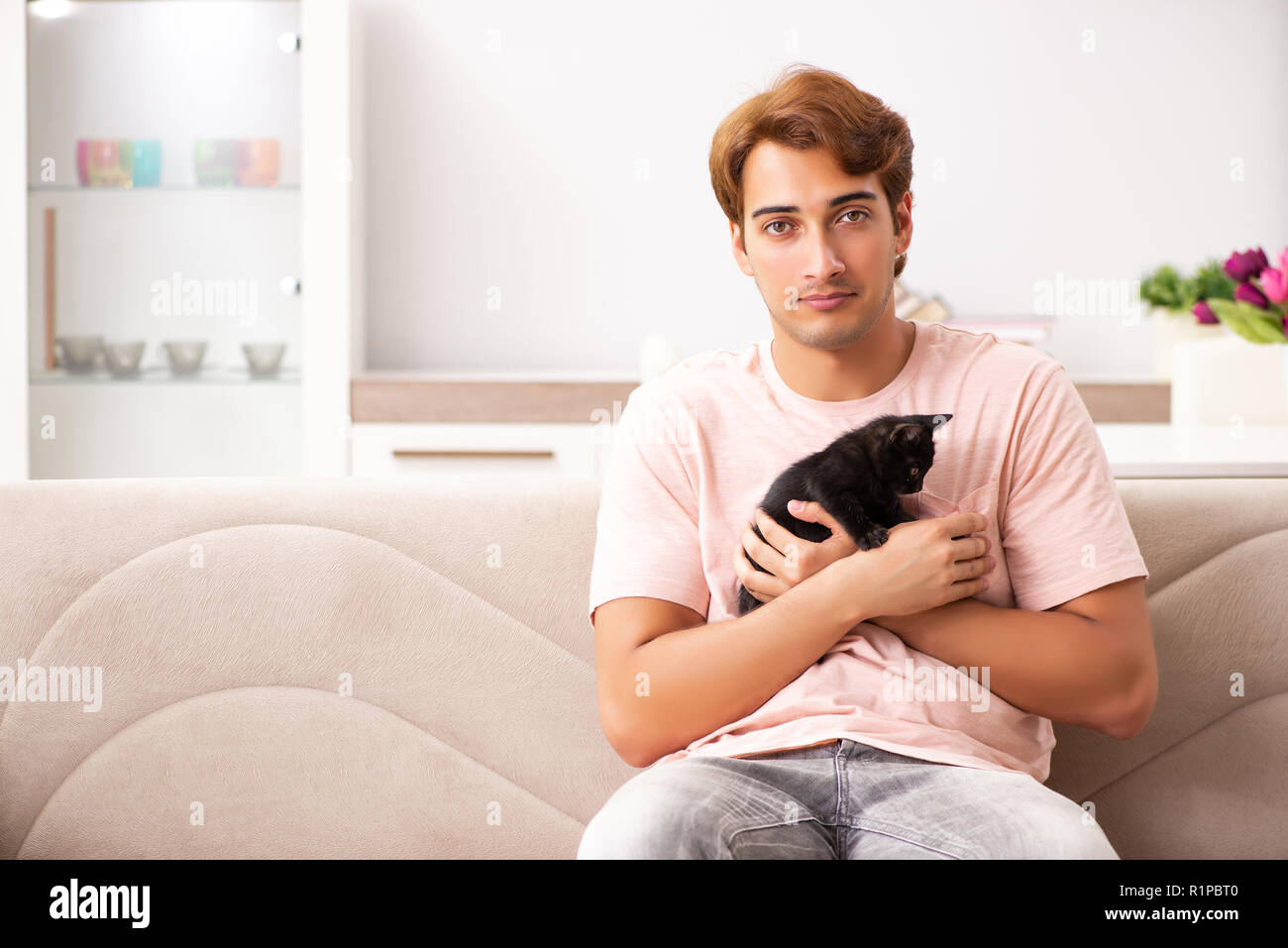 Young man playing with kitten at home Stock Photo - Alamy