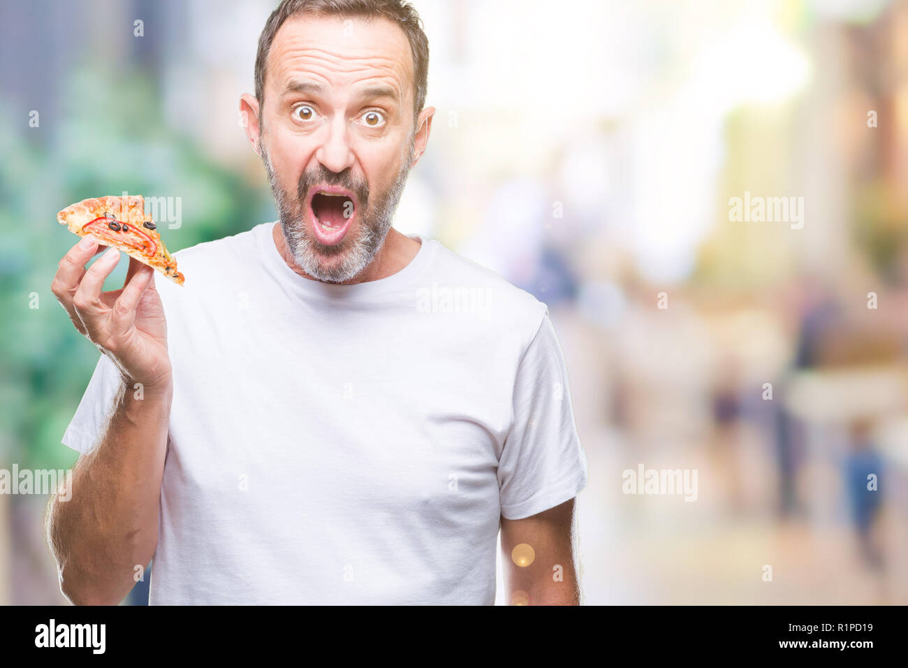 Middle age hoary senior man eating pizza slice over isolated background ...