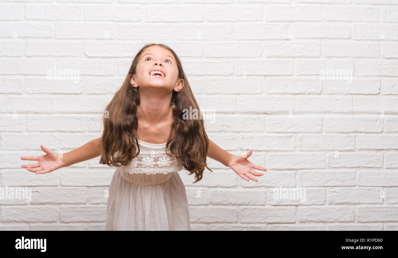Young hispanic kid over white brick wall crazy and mad shouting and ...