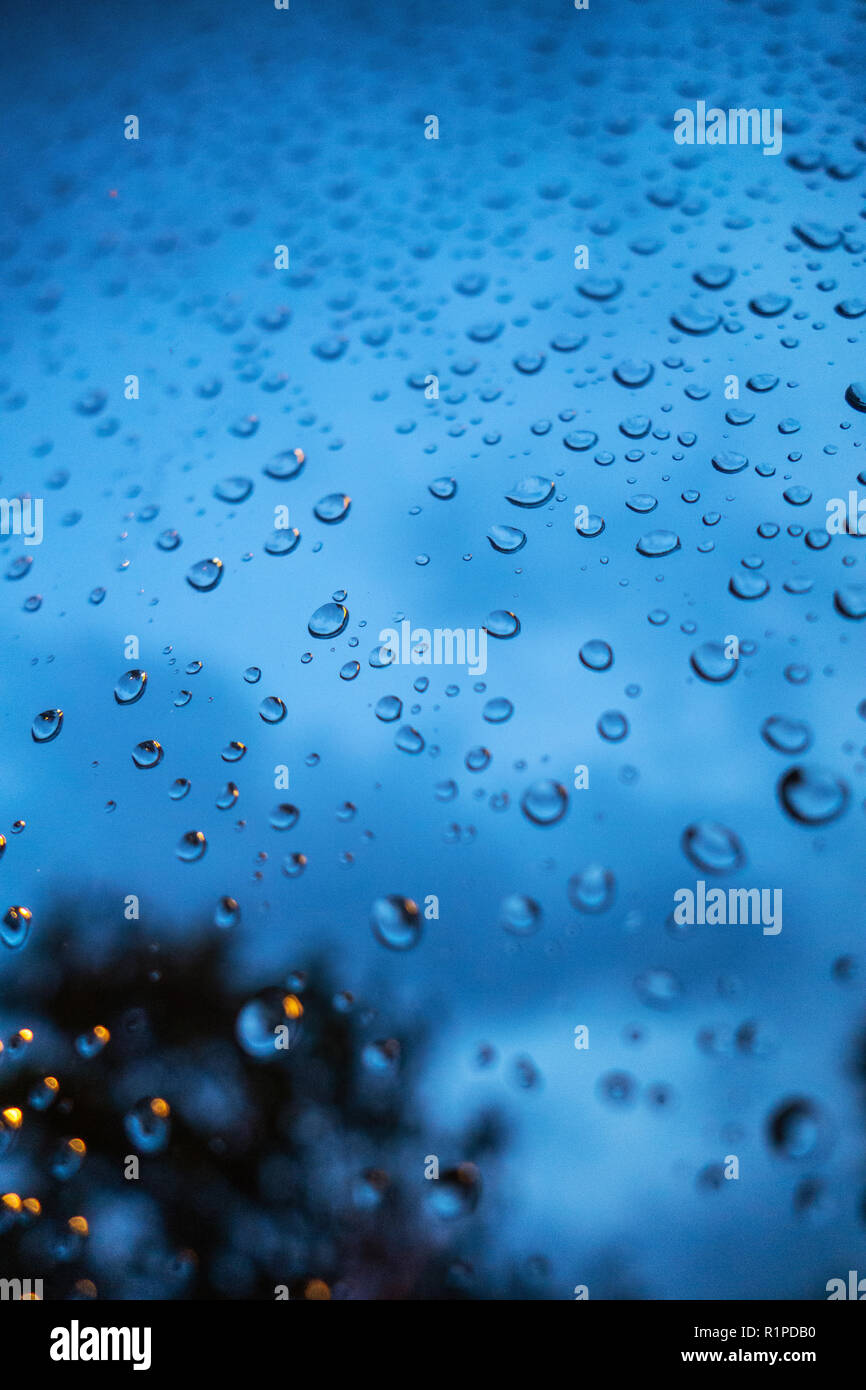 very closeup photograph of raindrops on glass window with dark sky in ...