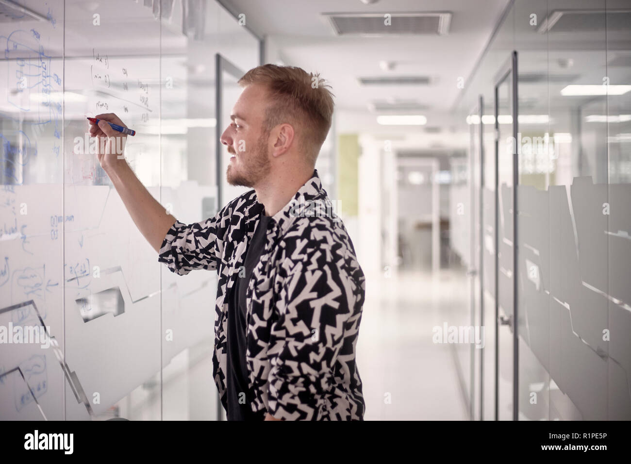 one young man, writing on glass window wall of modern office ideas ...
