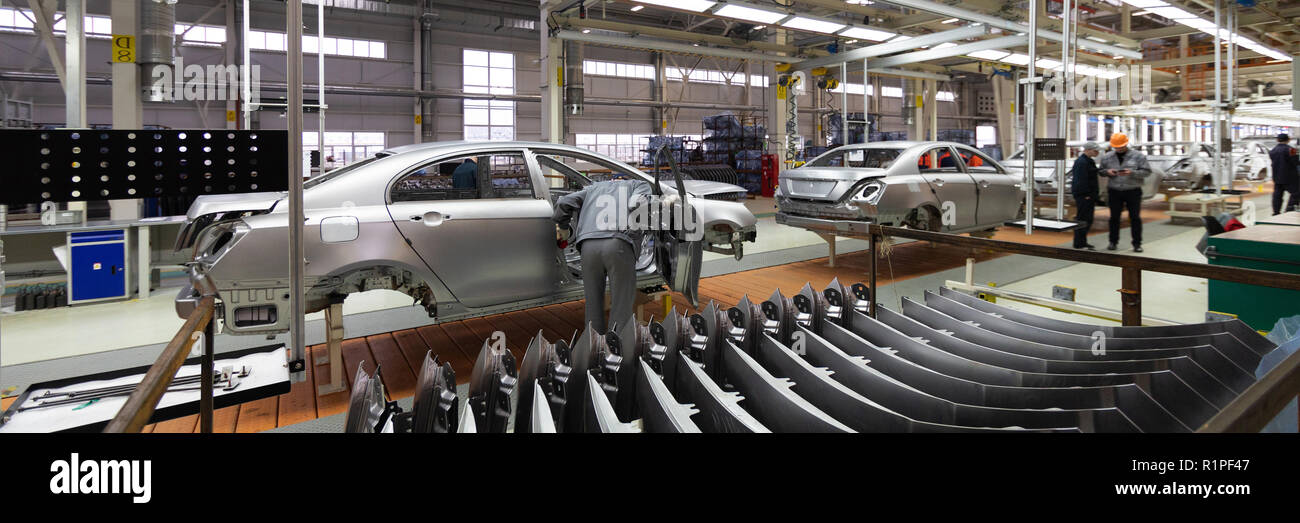 Engineer looks into the cab of the car on the production line ...