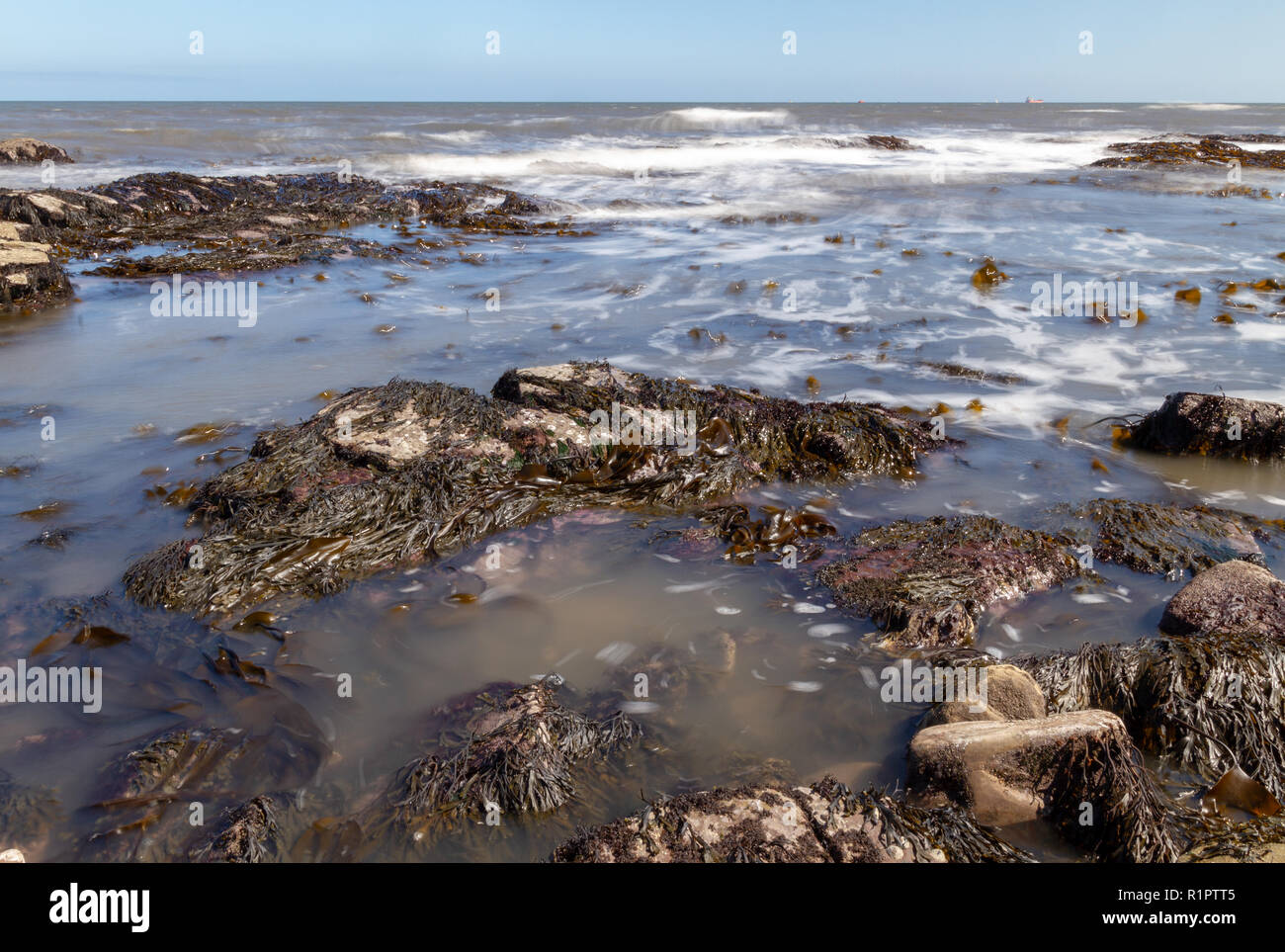 Rocky beach water waves with slow shutter motion blur Stock Photo - Alamy