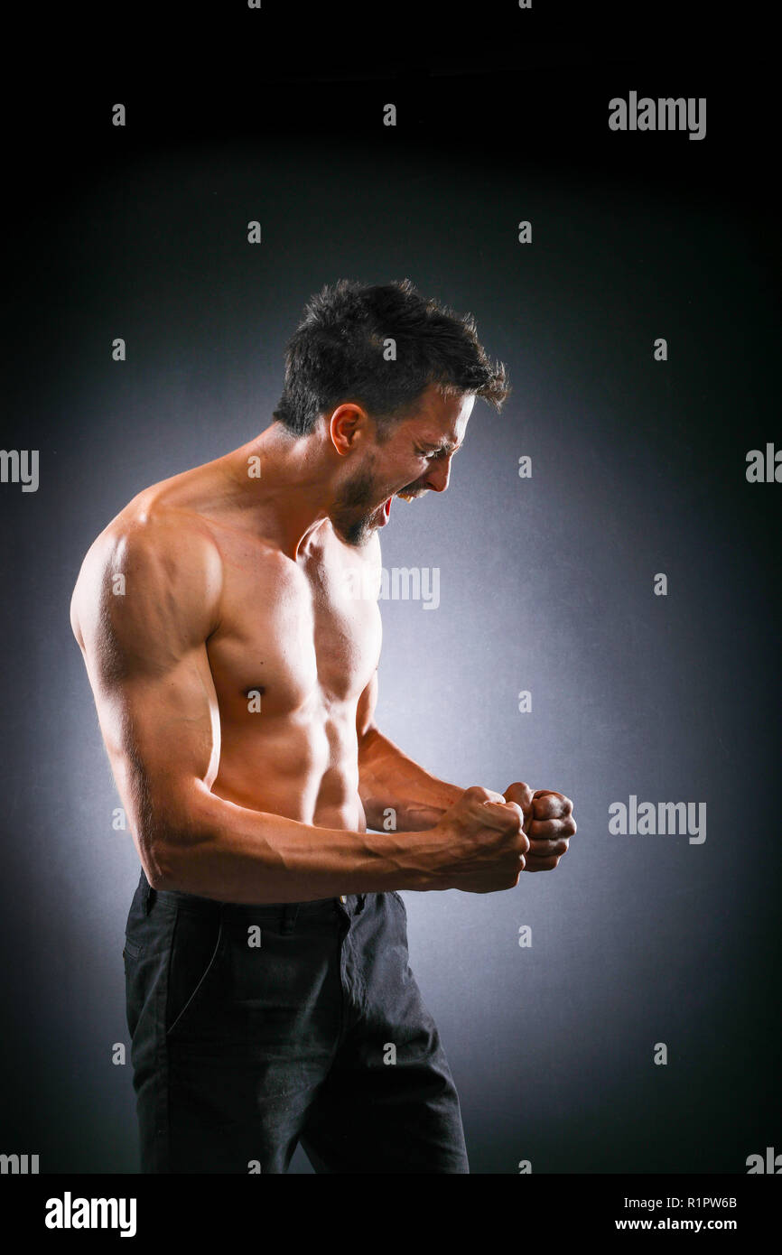 Macho man feeling victory and celebrate success with open mouth on dark ...