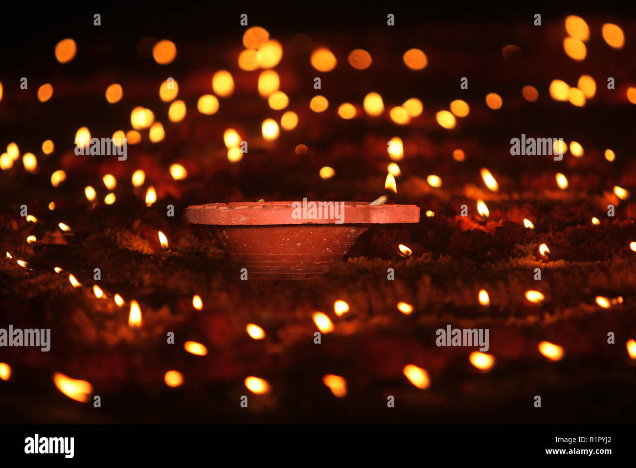 A Diwali earthen lamp kept in the center of marigold flowers and other ...