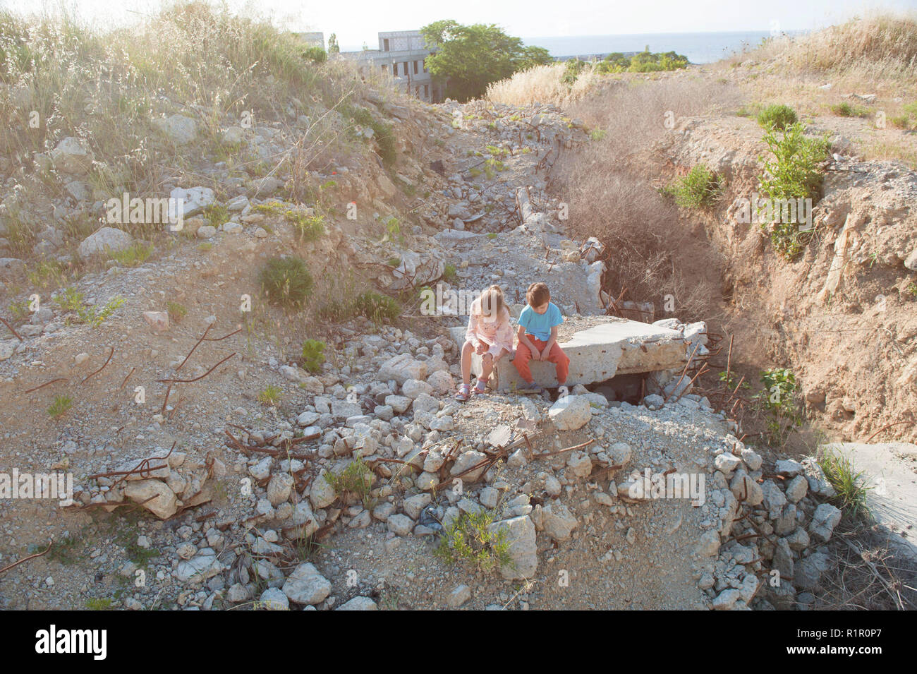 two poor refugee children boy girl on ruins building destroyed by air ...
