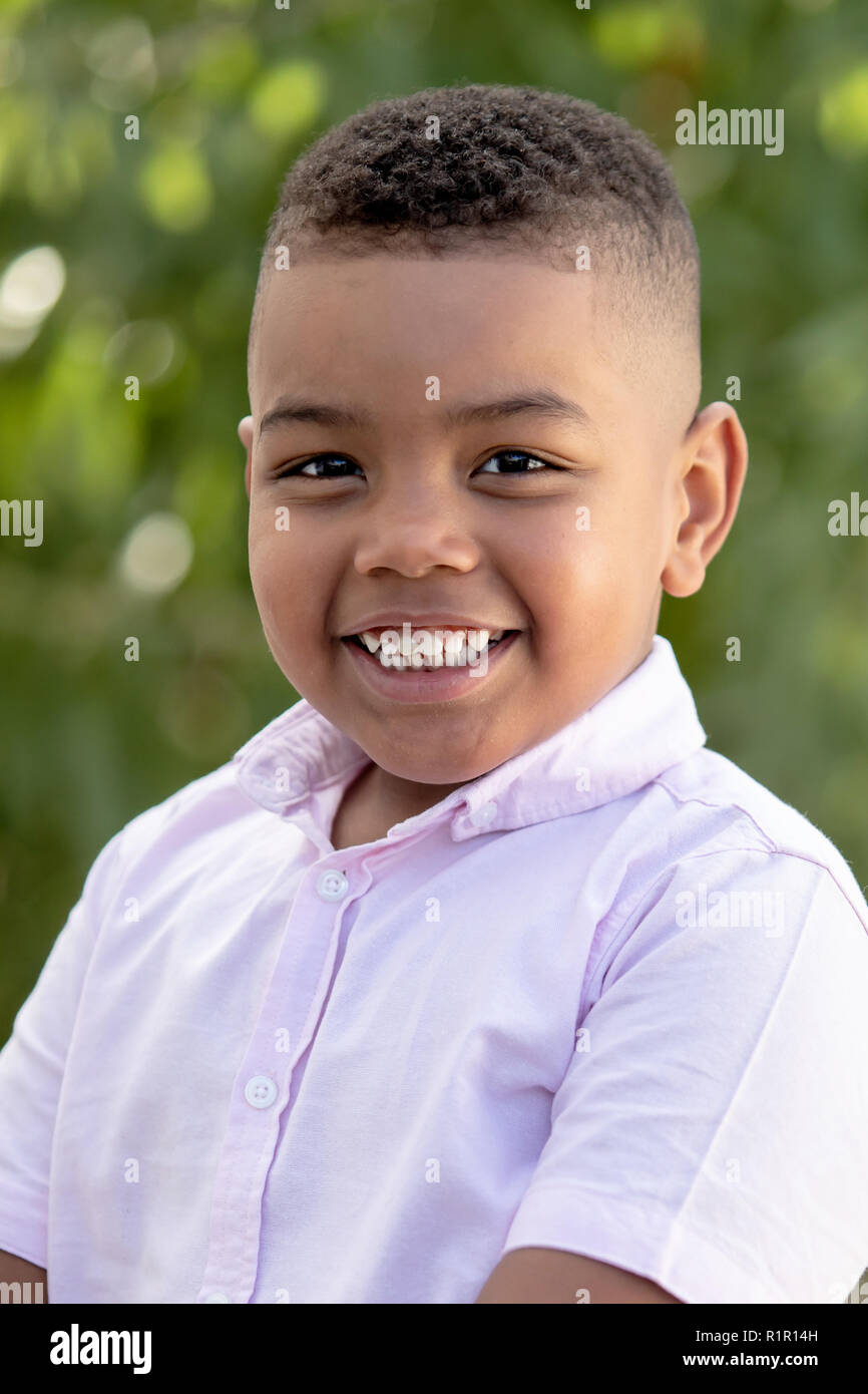 Adorable latin child in the garden with a beautiful green of background ...