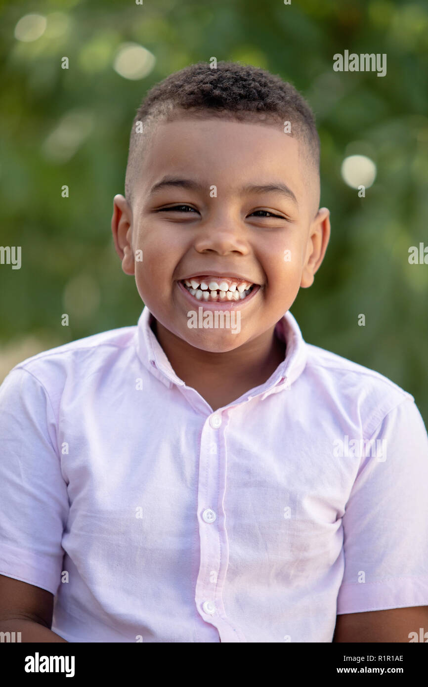 Adorable latin child in the garden with a beautiful green of background ...