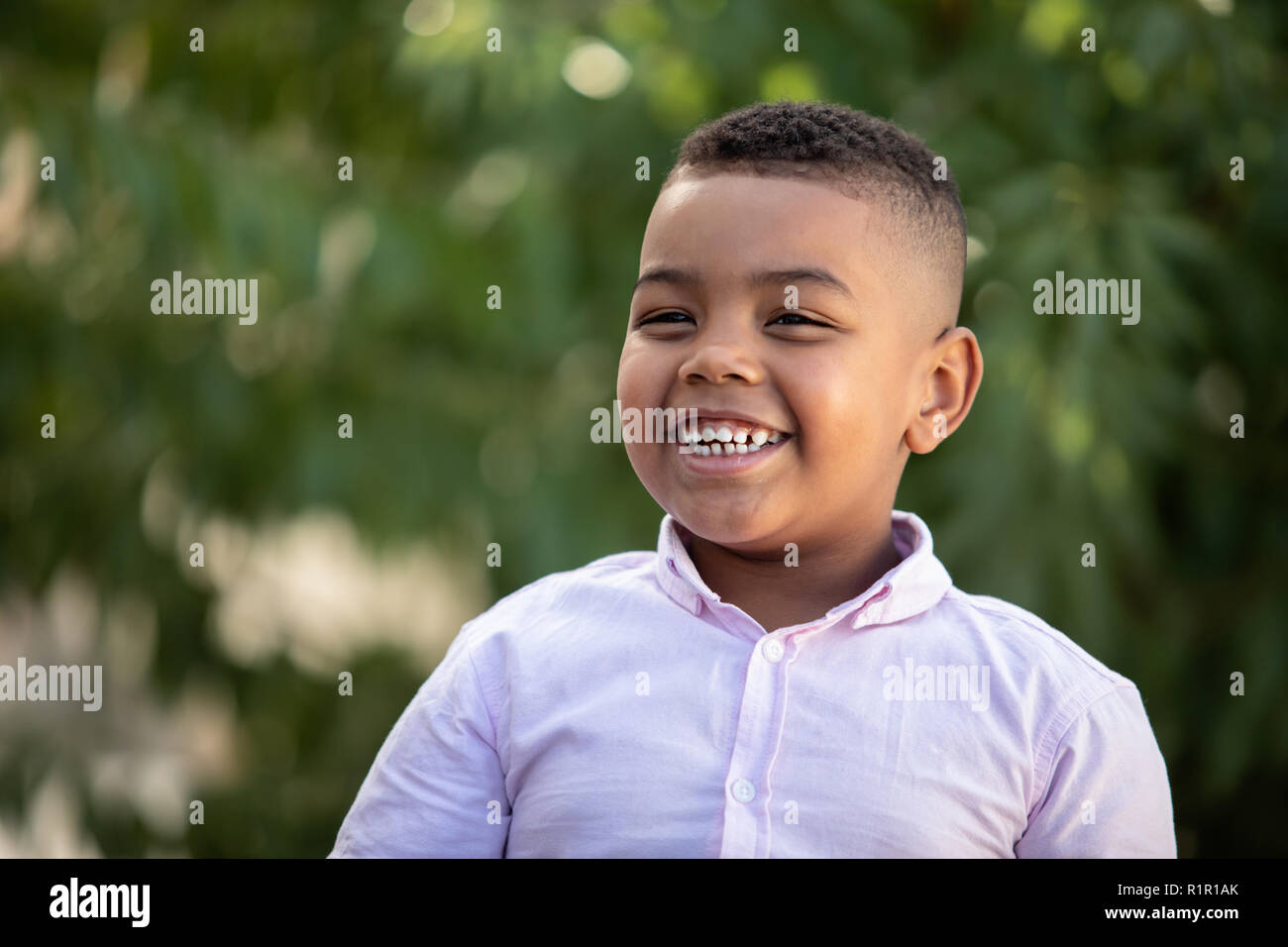 Adorable latin child in the garden with a beautiful green of background ...