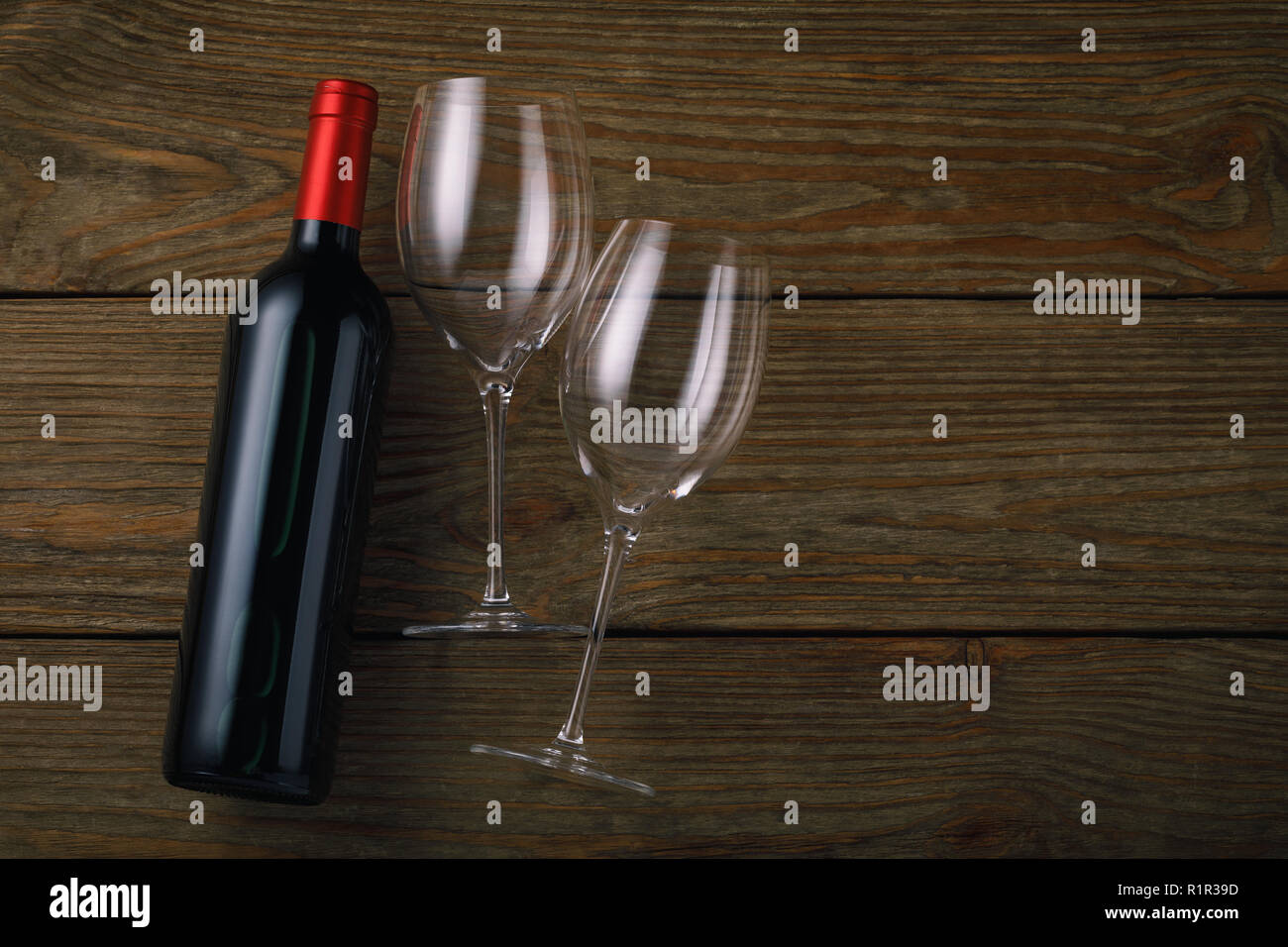 Bottle of red wine and two glasses on a wooden table with copy space ...