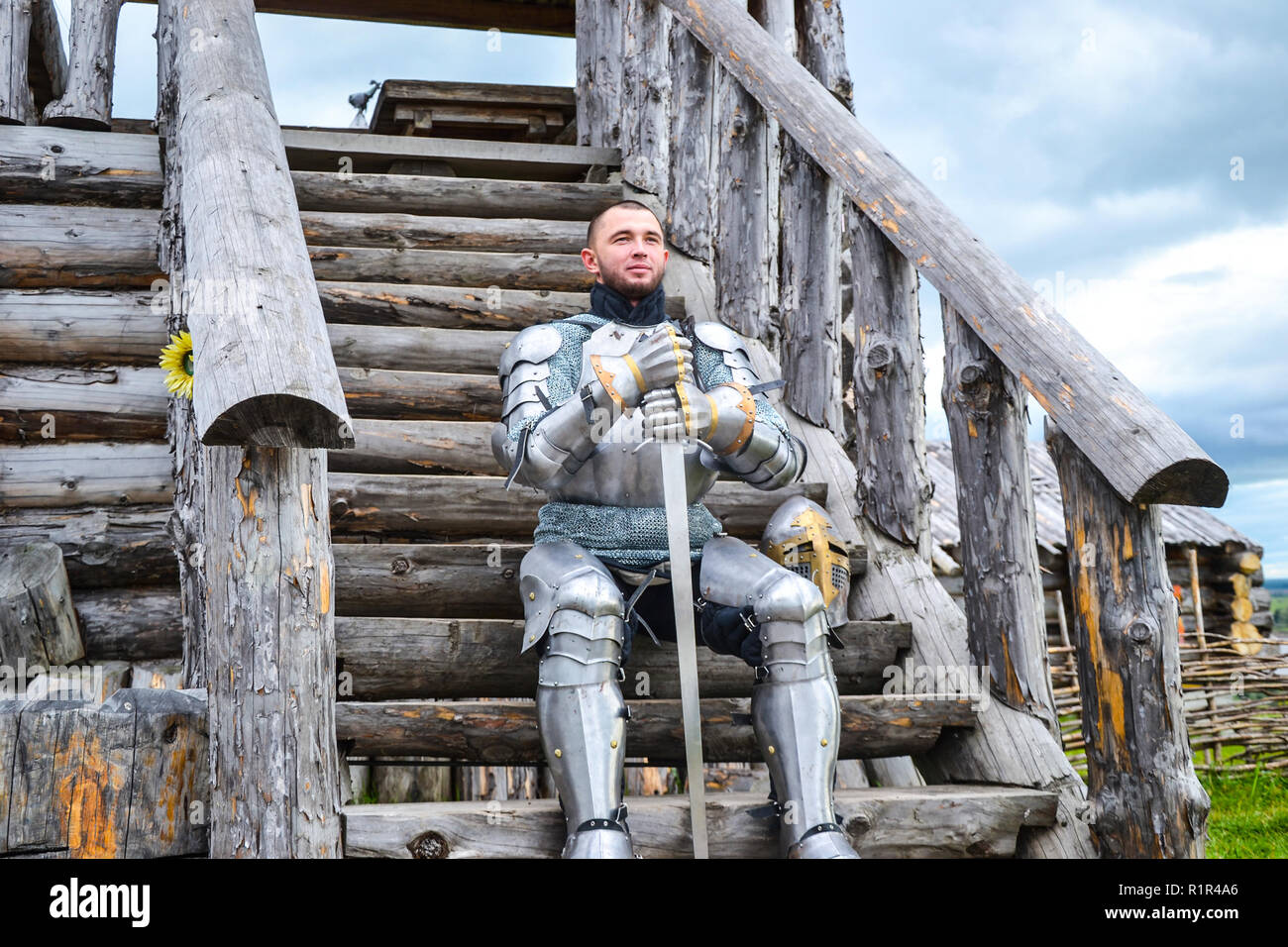 Knight in the armor on the wooden steps. Knightly armor and weapon ...