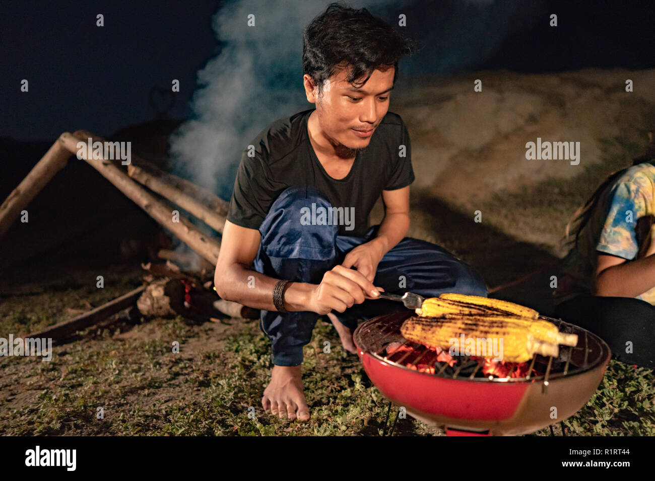 group of friends having fun camping, eat roasted corn and enjoy the ...