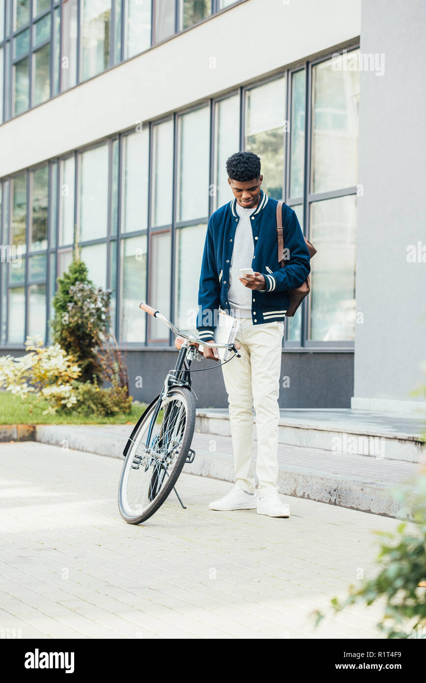 african american teleworker with documents using smartphone and ...