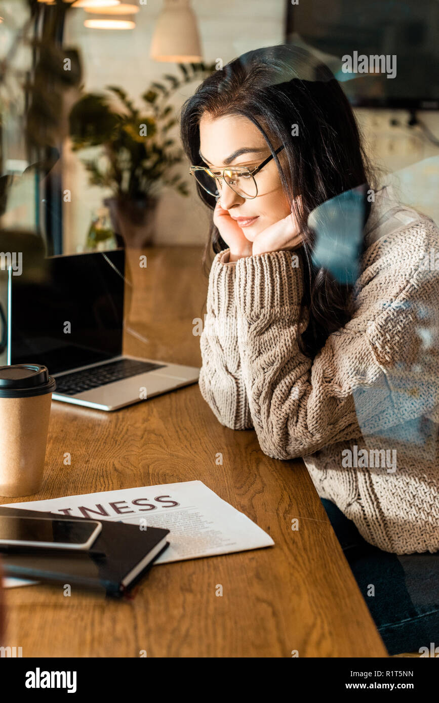 bored freelancer in cafe with laptop, smartphone and business newspaper ...