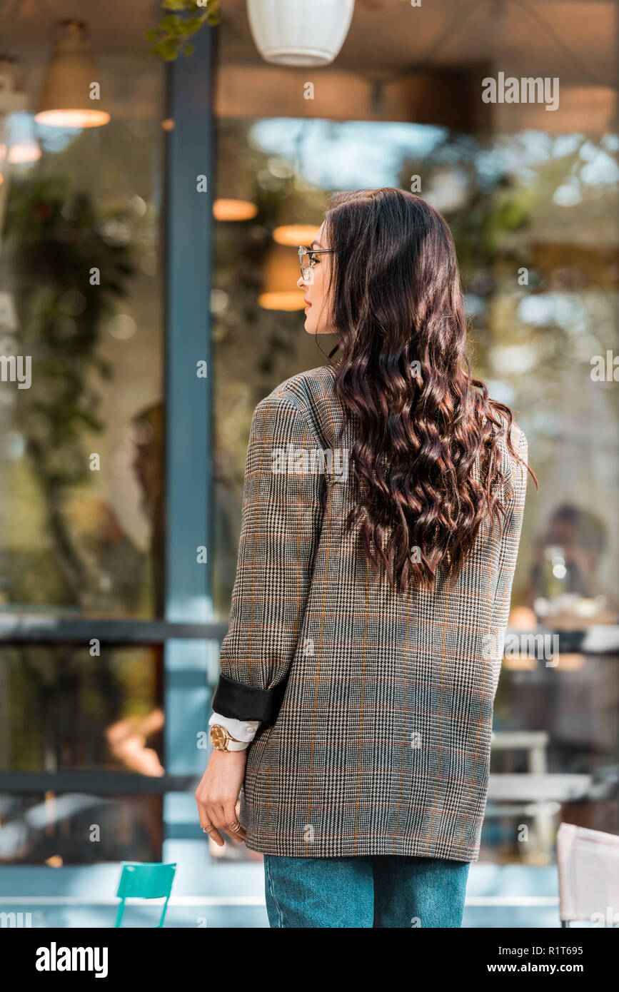 back view of beautiful woman in autumn outfit standing on street near ...