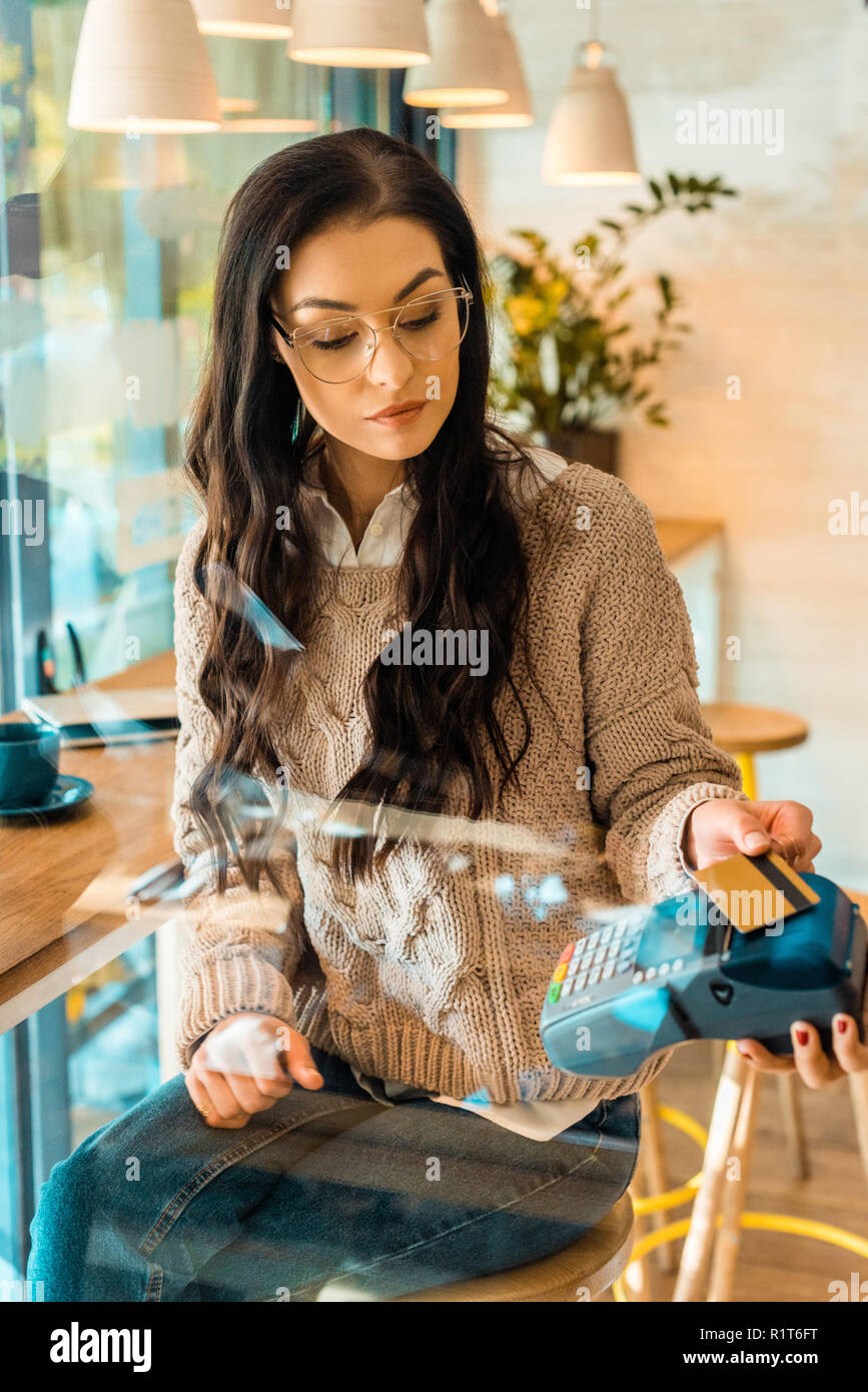 beautiful woman paying with credit card by contactless payment in cafe ...