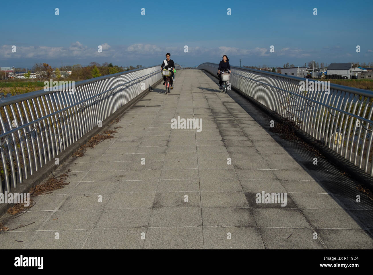 Riding bikes across a pedestrian bridge in Moerenuma Park in Sappor ...