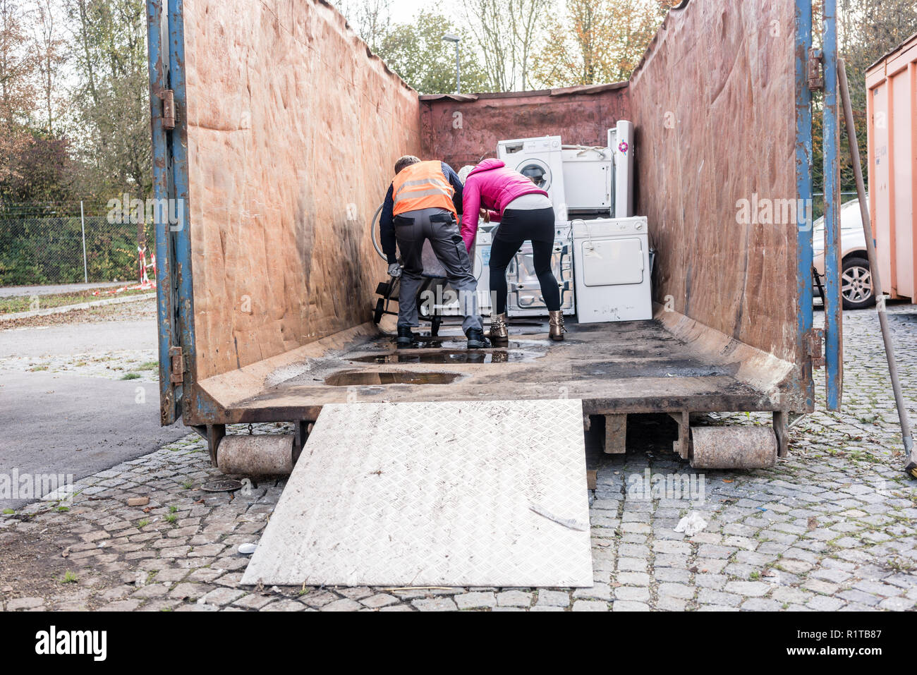 Woman and man giving electrical appliances to recycling center, a ...