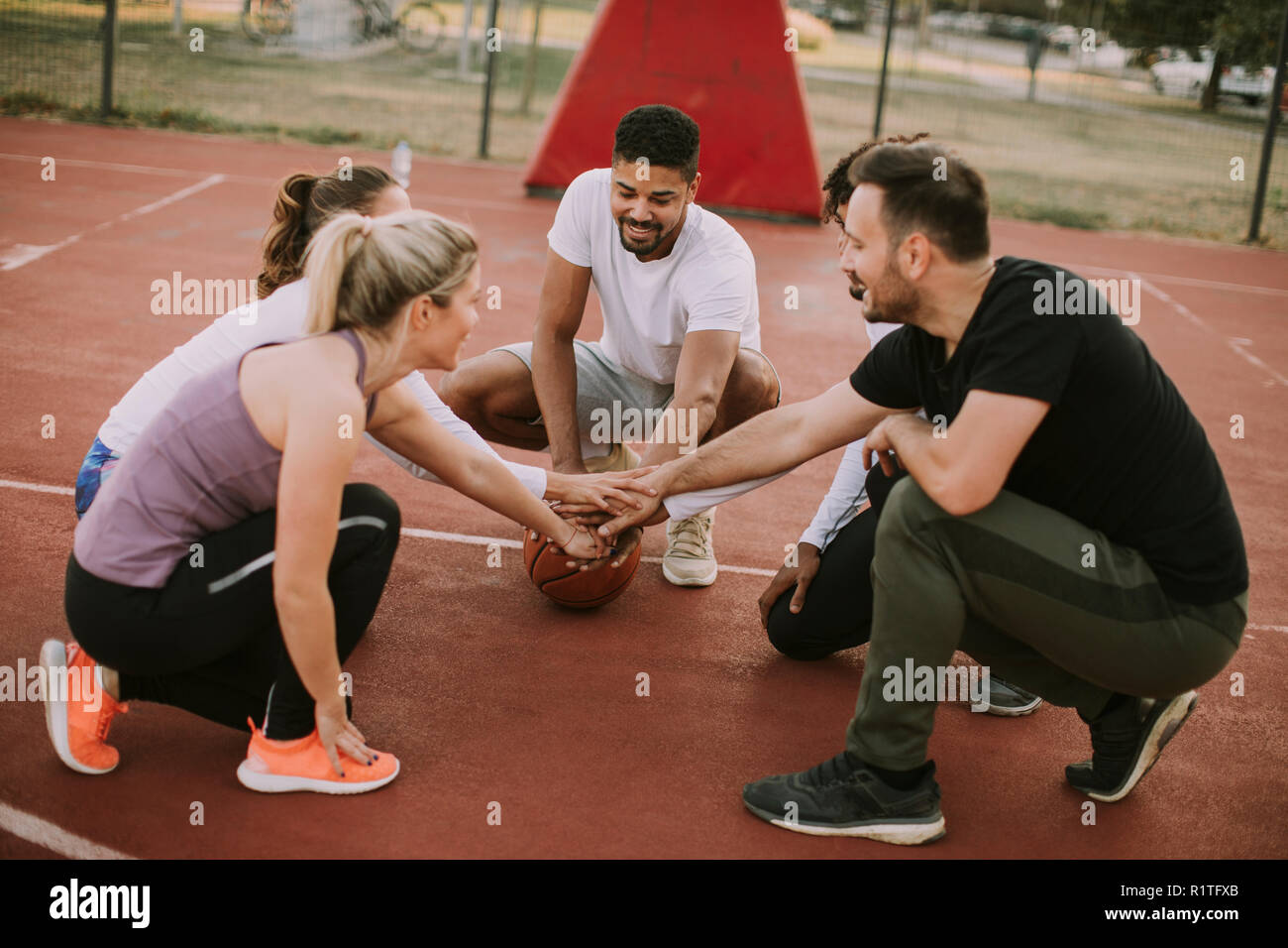 Multiethnic group of basketball players resting on court together Stock ...