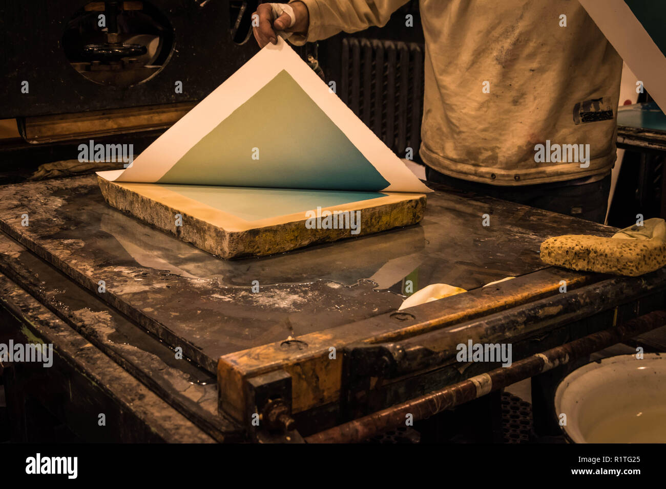 Man printing lithography. Removing paper from the stone Stock Photo - Alamy