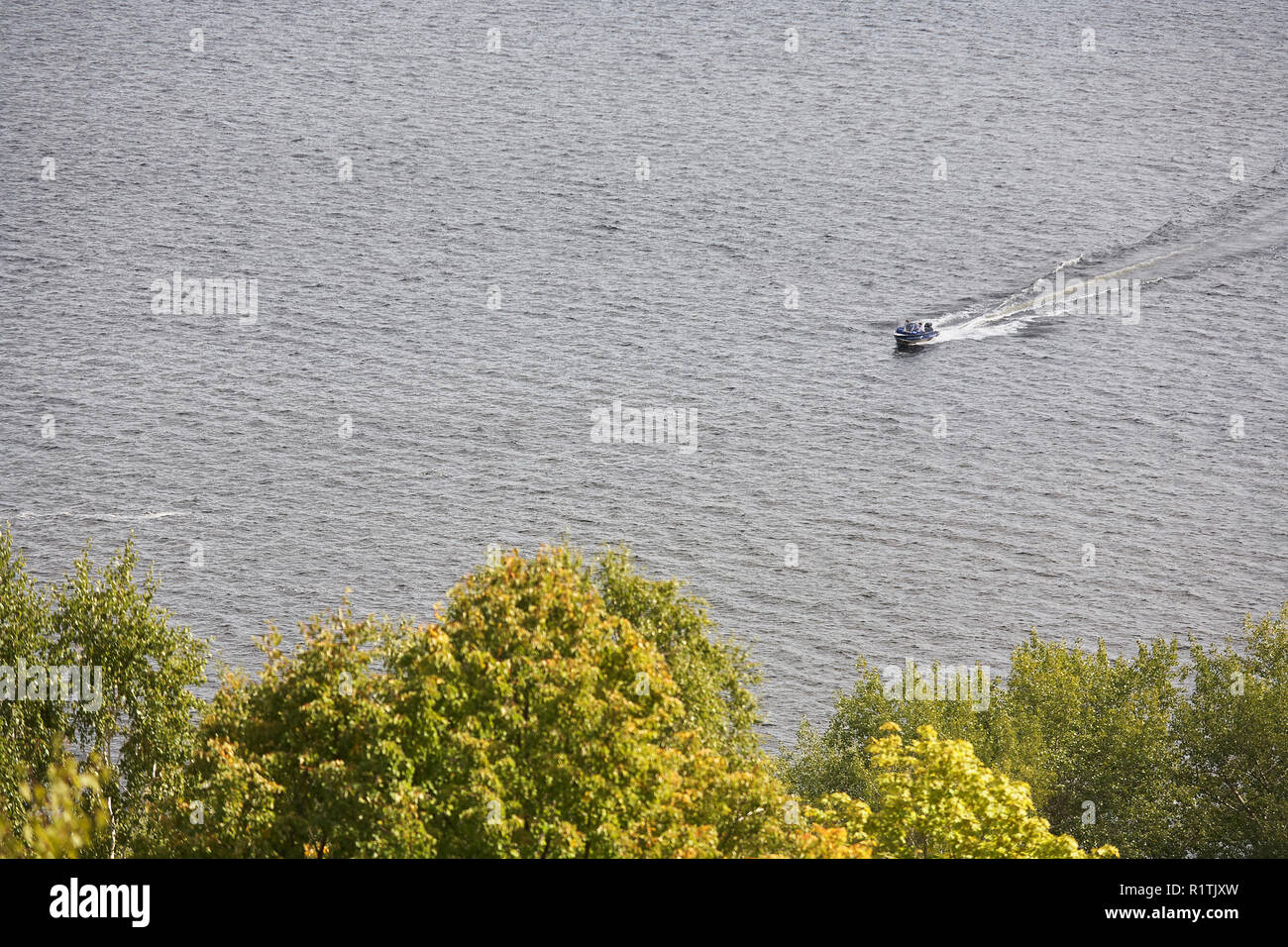 Small boat sailing down the river on a background of trees Stock Photo ...