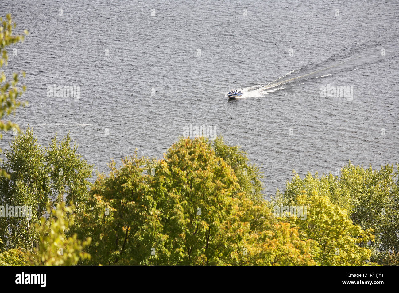Small boat sailing down the river on a background of trees Stock Photo ...