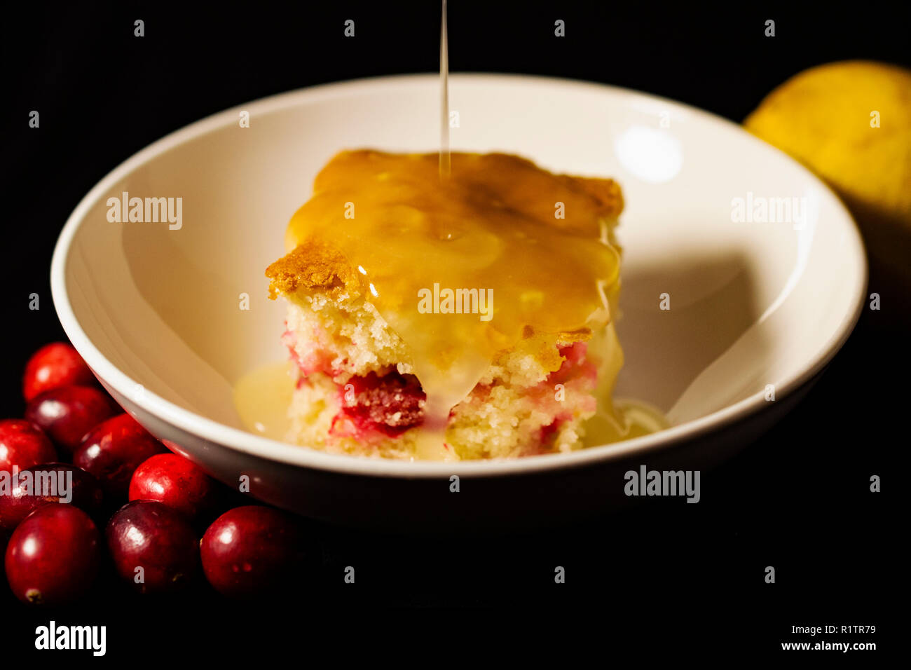 Slice of Cranberry Cake drizzled with Lemon Sauce in shallow white bowl ...