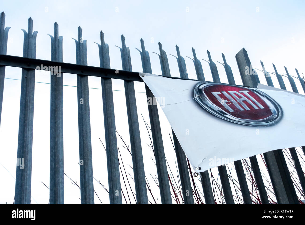 Banner on a fence outside a closed and abandoned FIAT car dealership at ...