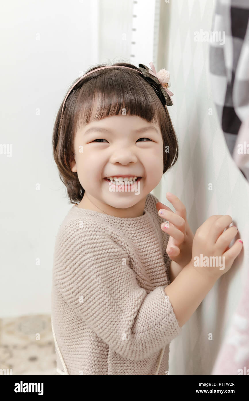 Little pretty Asian girl standing in a normal indoor life background ...