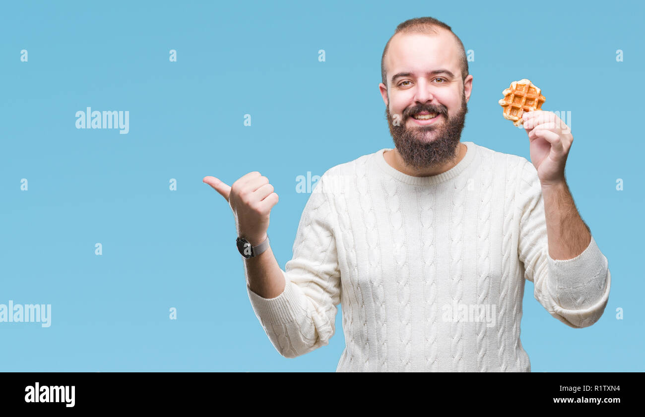 Young caucasian hipster man eating sweet waffle over isolated ...