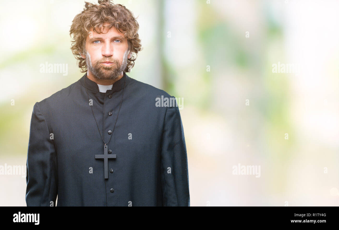 Handsome hispanic catholic priest man over isolated background puffing ...