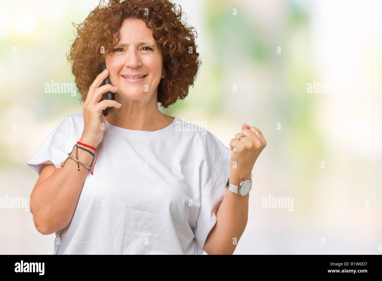 Middle ager senior woman talking on smartphone over isolated background ...