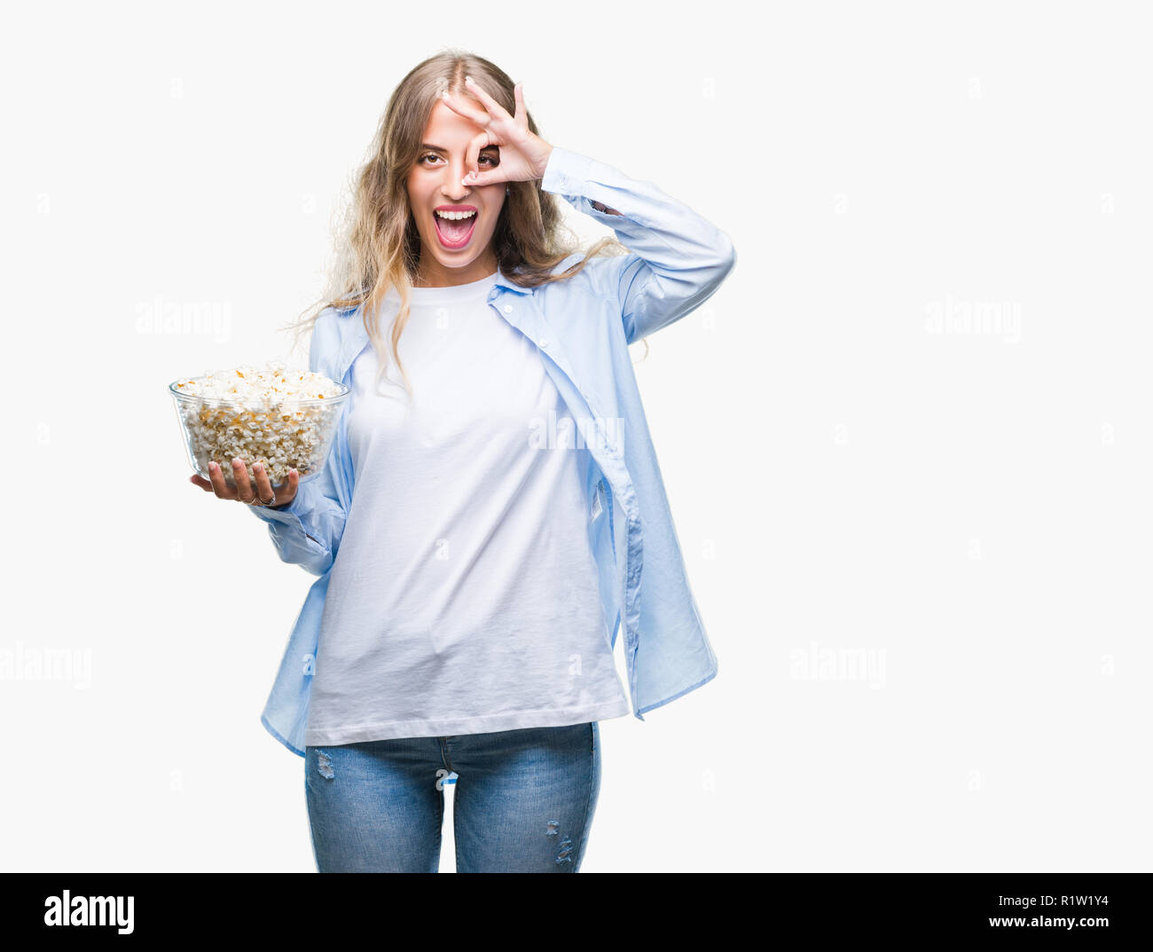Beautiful young blonde woman eating popcorn over isolated background ...