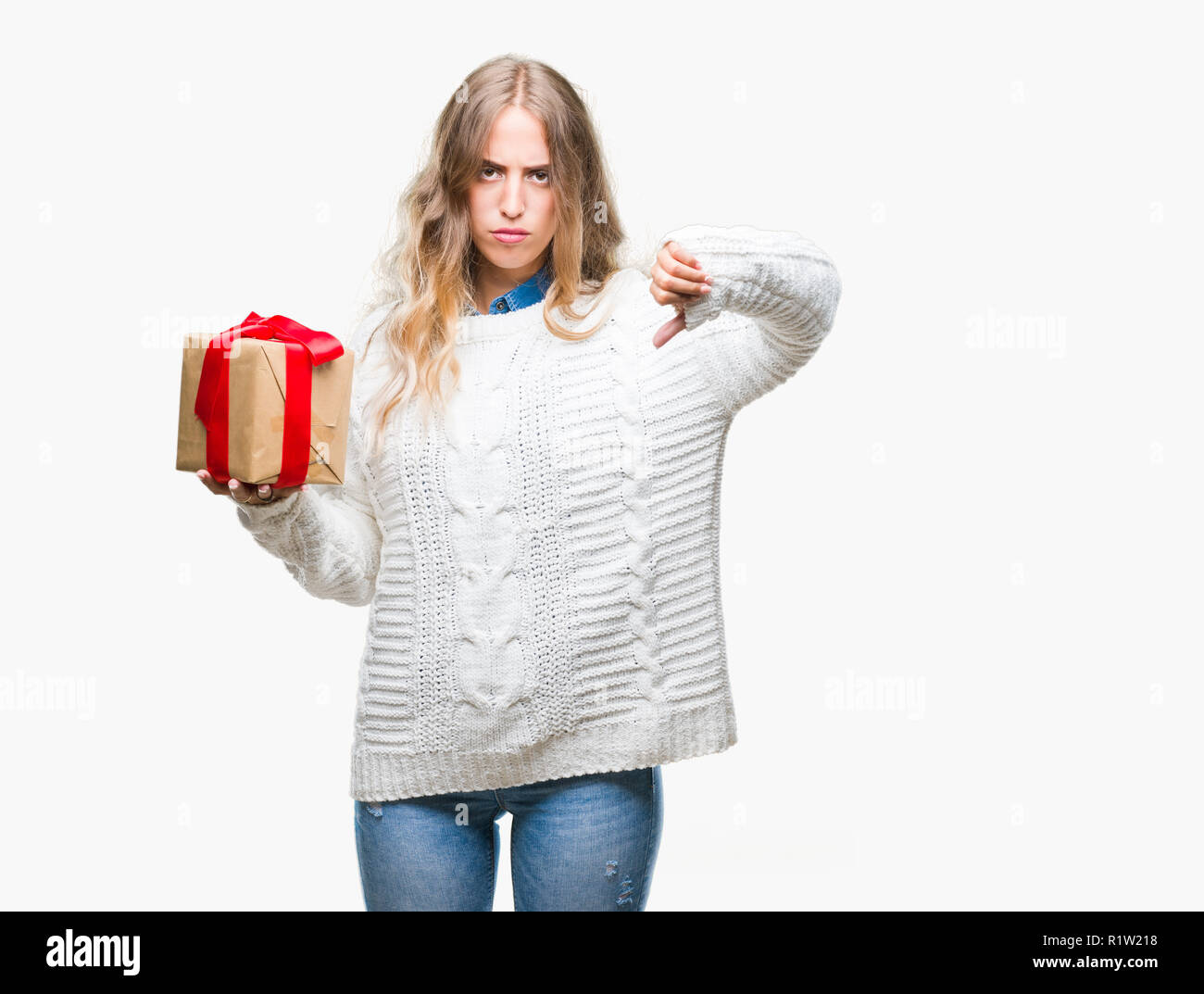 Beautiful young blonde woman holding gift over isolated background with ...