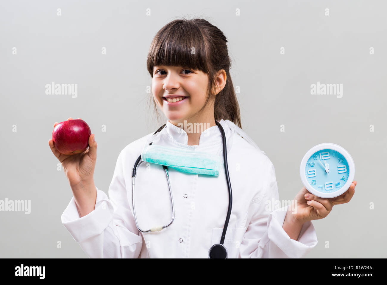 Little doctor is giving advice that is time to eat fruit by holding ...