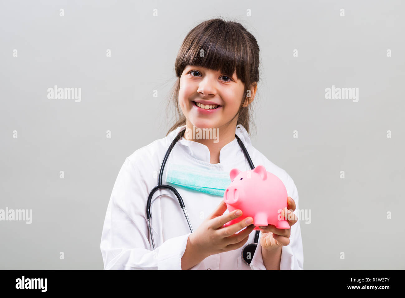 Cute little doctor holding piggy bank Stock Photo - Alamy