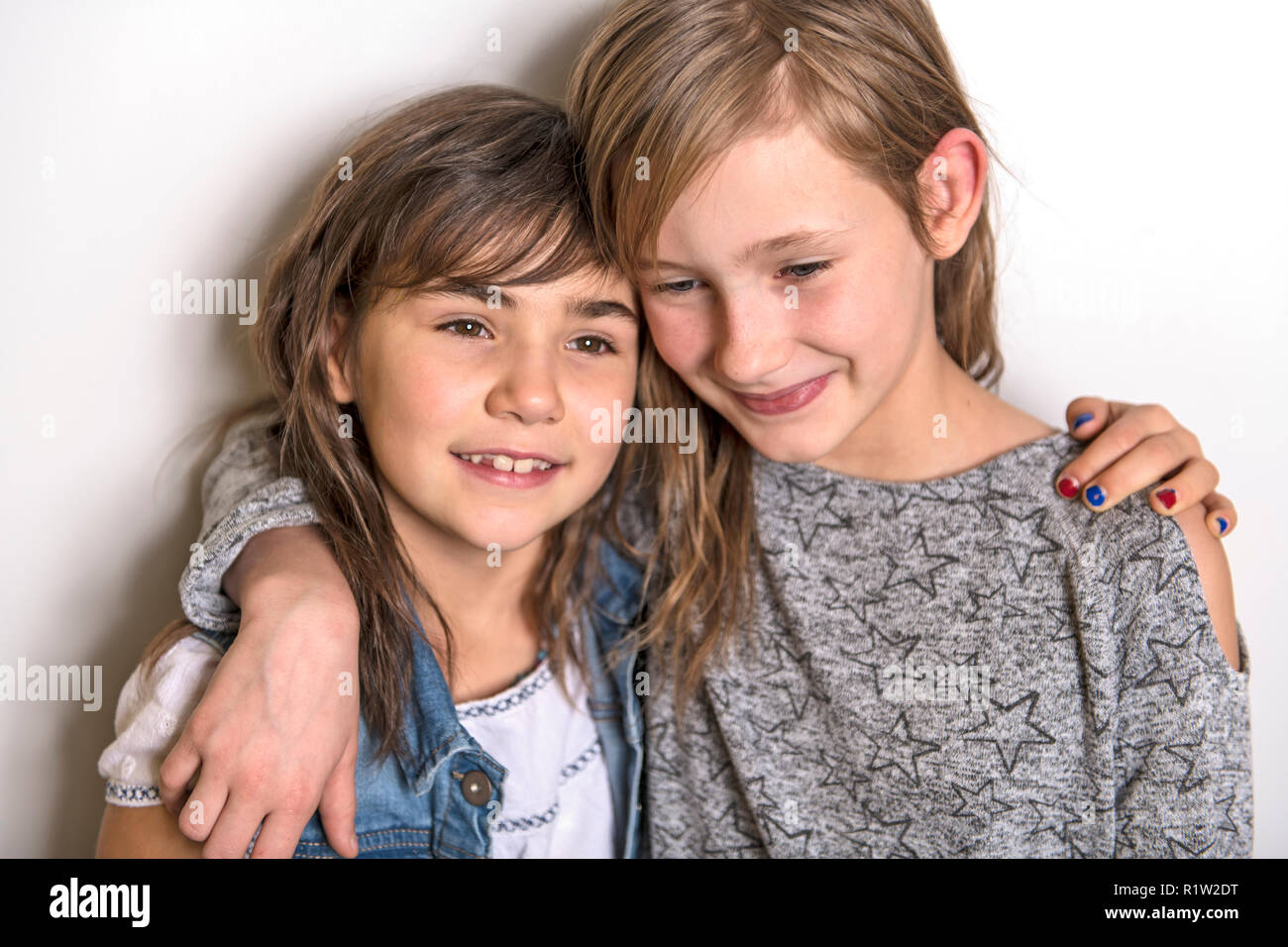 Two nice and happy kids standing at blank grey wall and embracing Stock ...